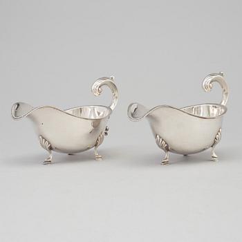 A pair of Silver sauce boast made with scroll handle and sitting on ...