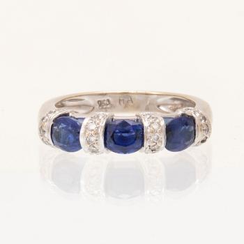An 18K white gold ring set with oval brilliant cut sapphires and round ...